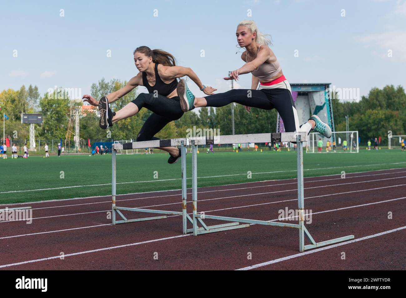 Two athlete woman runnner running hurdles at the stadium outdoors Stock ...