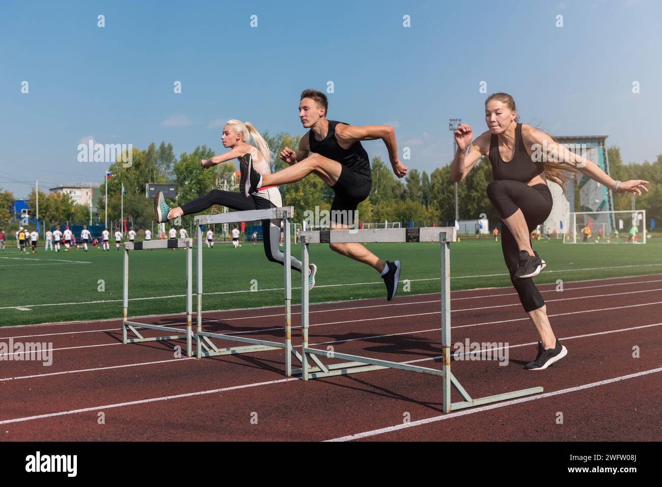 Two athlete woman and man runnner running hurdles at the stadium ...