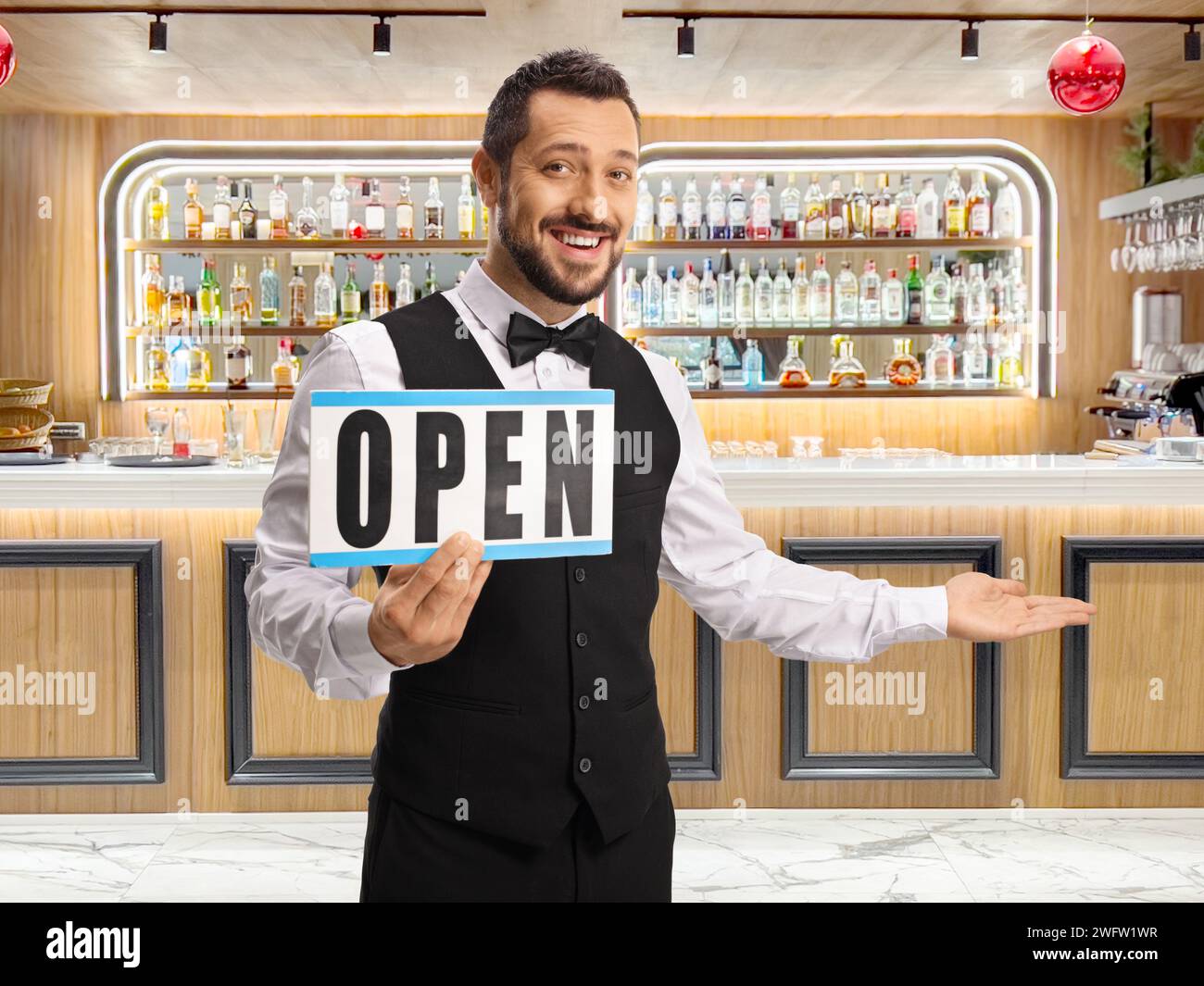 Waiter holding a sign open and gesturing welcome at a cafe bar Stock ...