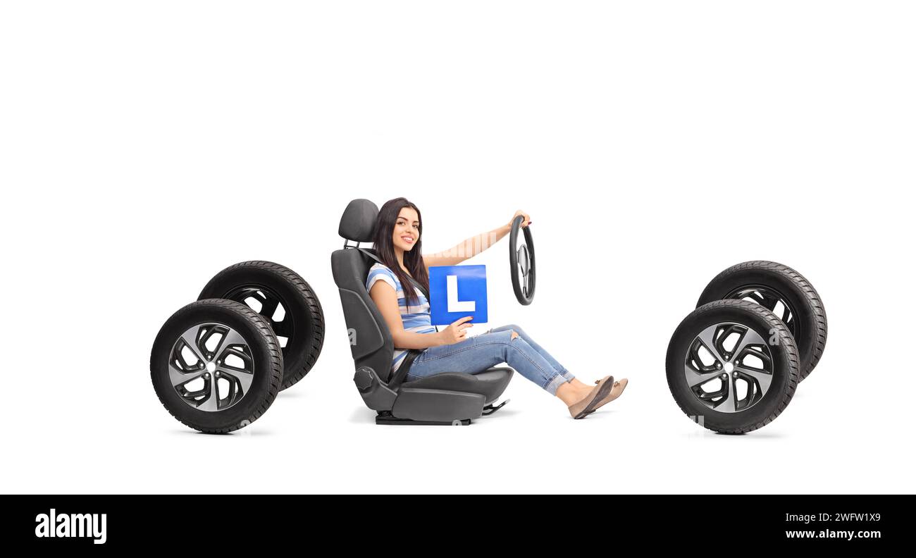 Young woman holding a learner plate and a steering wheel seated on a ...