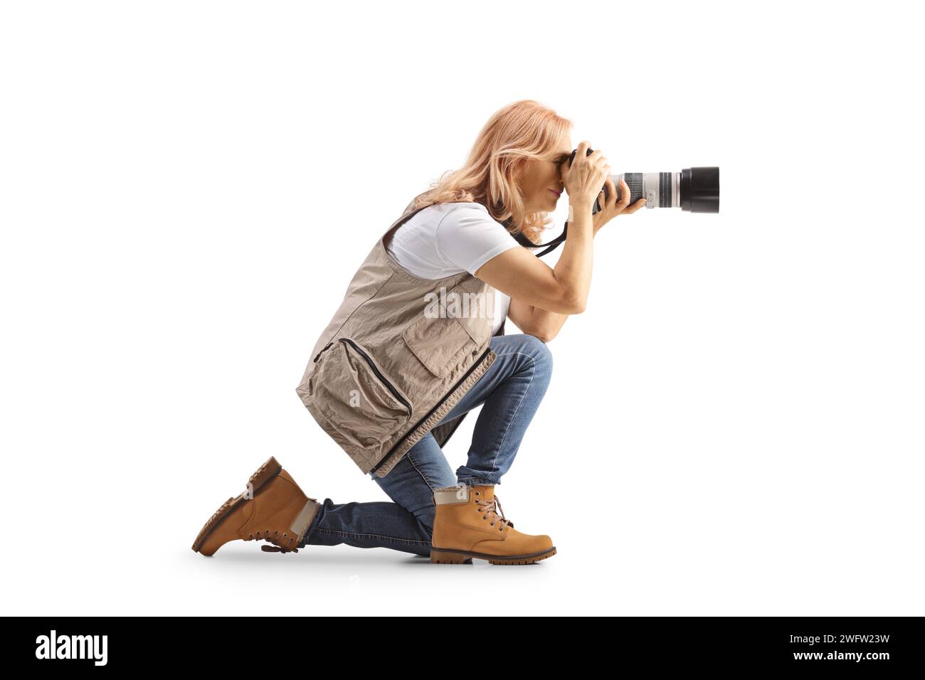 Full length profile shot of a female photographer kneeling and taking a ...