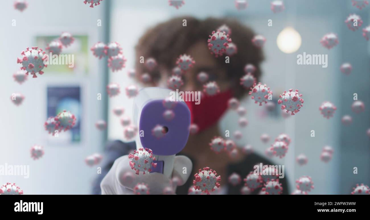 Image of covid 19 cells over woman using digital thermometer, wearing ...