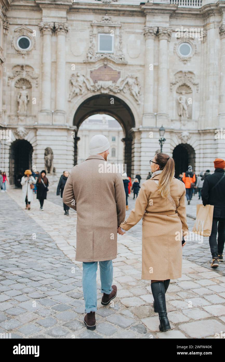 Two individuals stroll hand in hand amidst urban scenery, passing by a ...