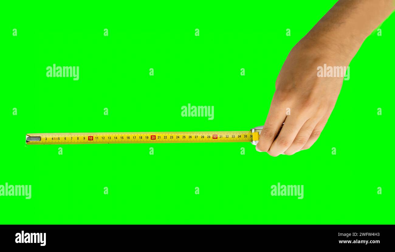 hand with tape measure taking measurements on isolated cutout on green ...