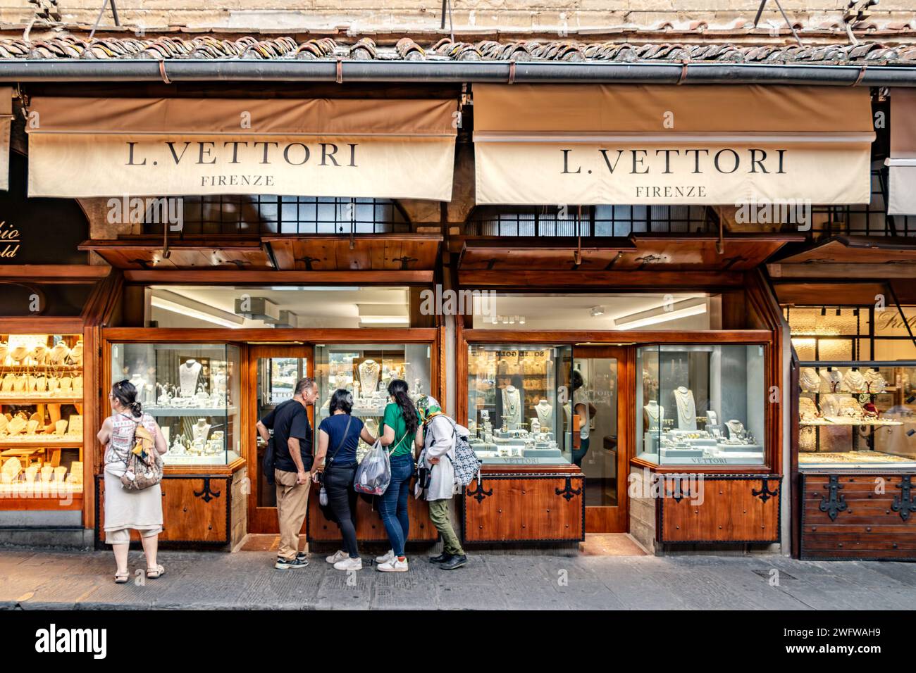 Crowds of people walking on the Ponte Vecchio bridge browsing the many jewellery shops which ...