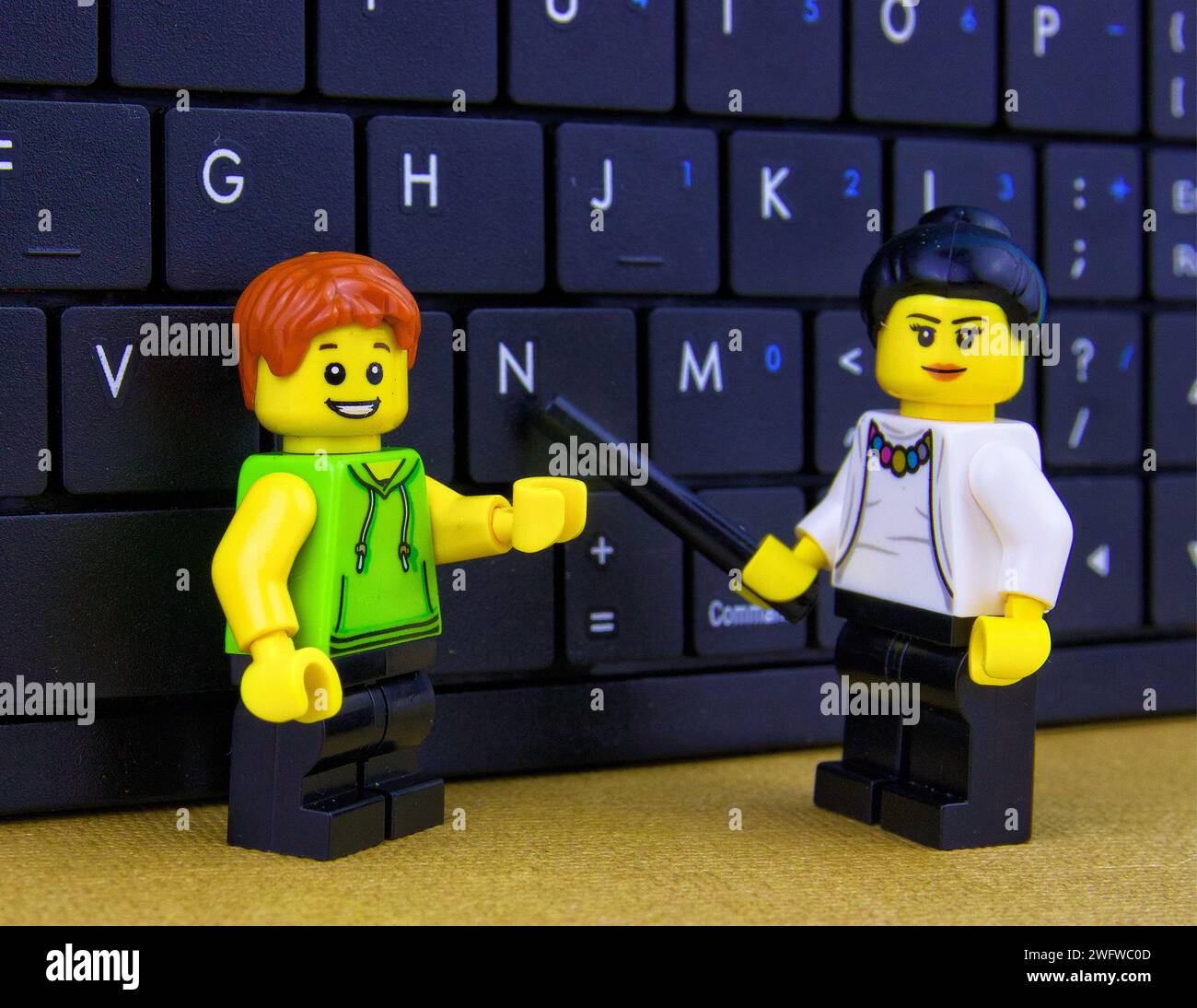 Toy, smiling mini figures standing in front of a qwerty computer ...