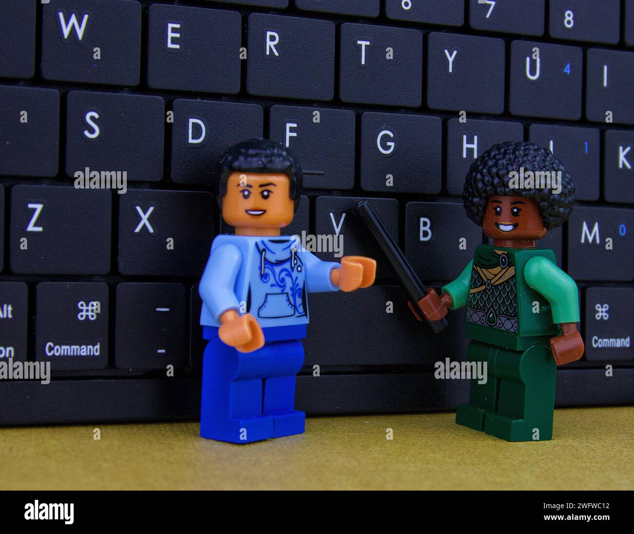 Toy, smiling mini figures standing in front of a qwerty computer ...