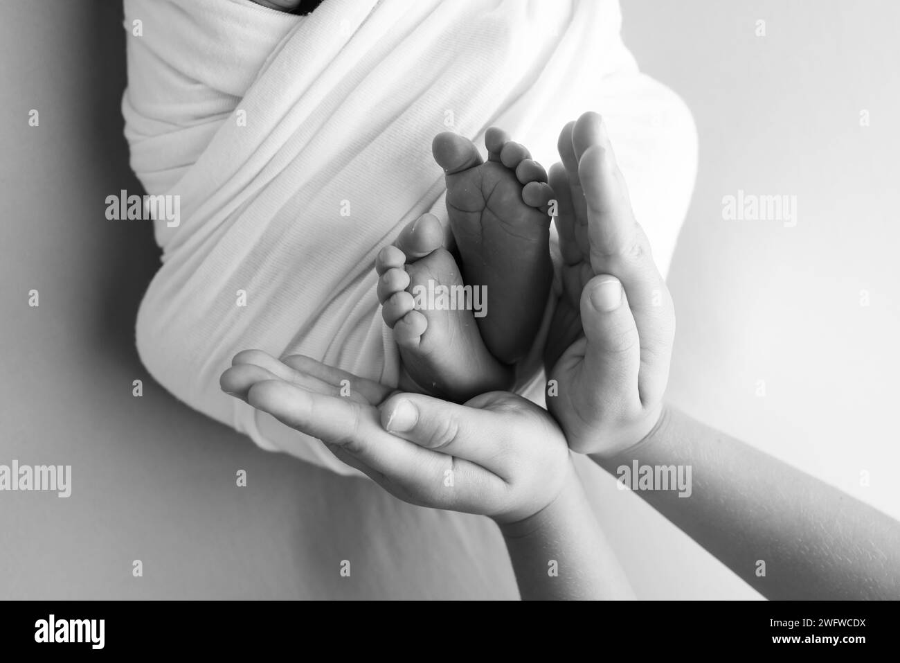 The palms of the father, the mother are holding the foot of the newborn ...