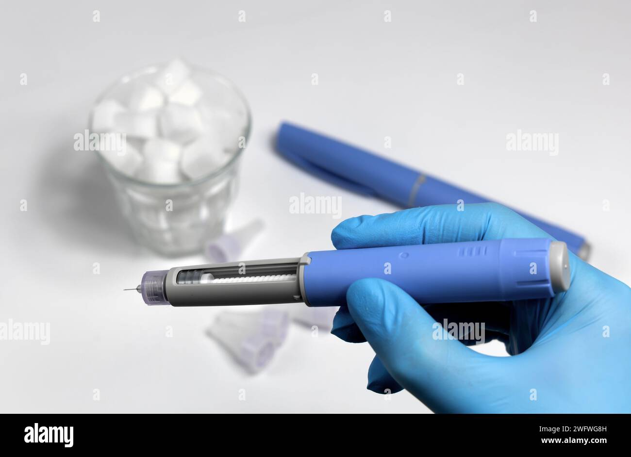 Hands in blue surgical gloves holding Ozempic Insulin injection pen for ...