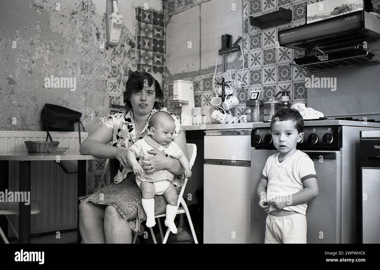 1980s, historical, a mother with her infant child and young son her in ...