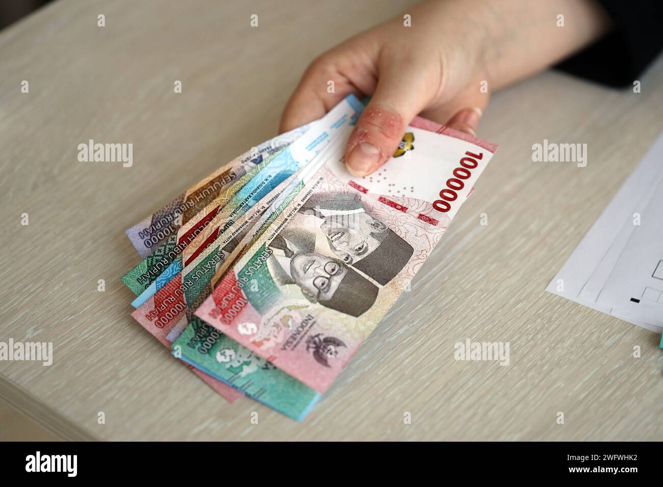 Female accountant hand give bunch of many indonesian rupiah money bills ...