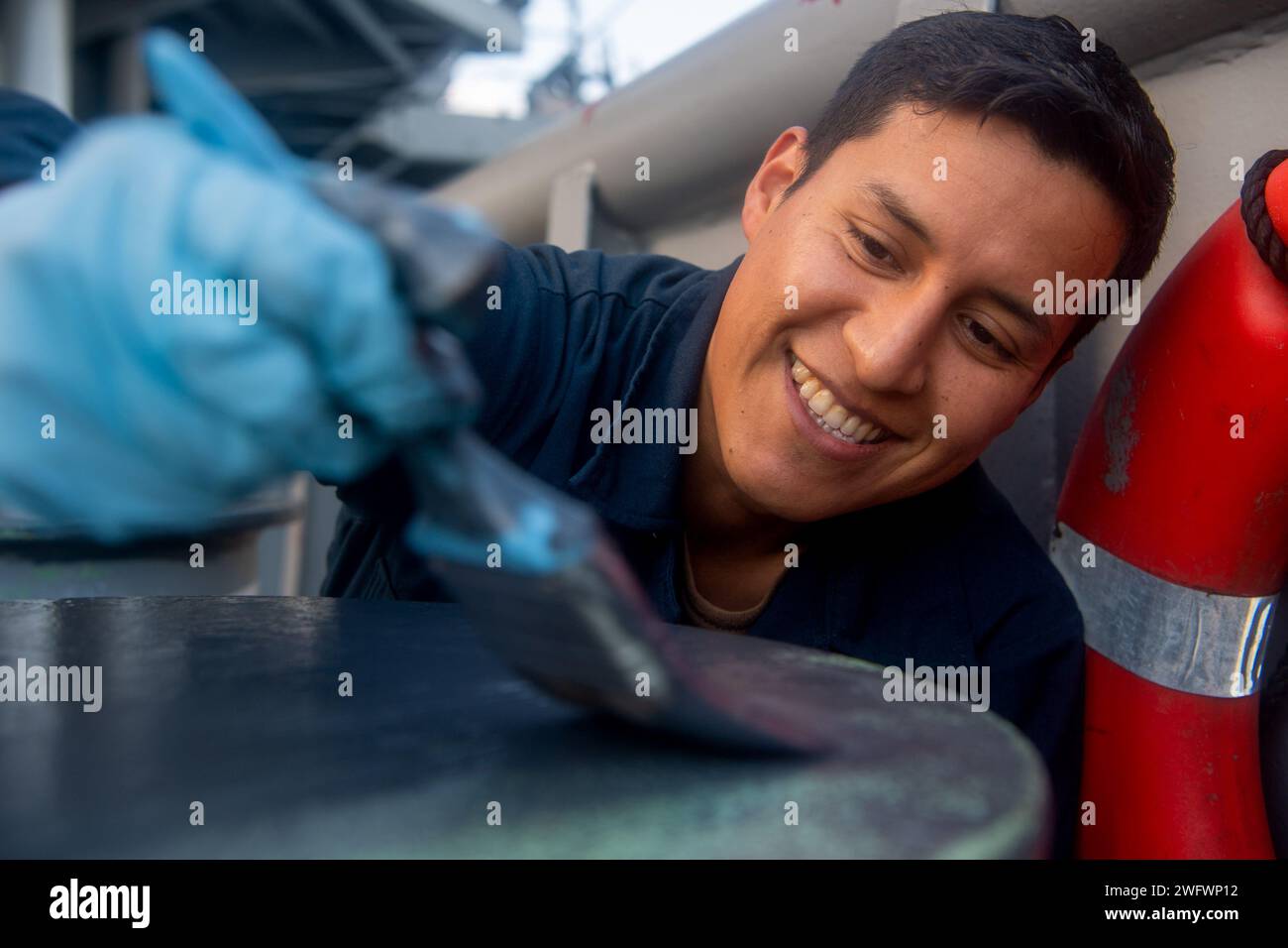 Seaman David Sarango, a native of Elizabeth, New Jersey, paints the bit on the fantail aboard ...