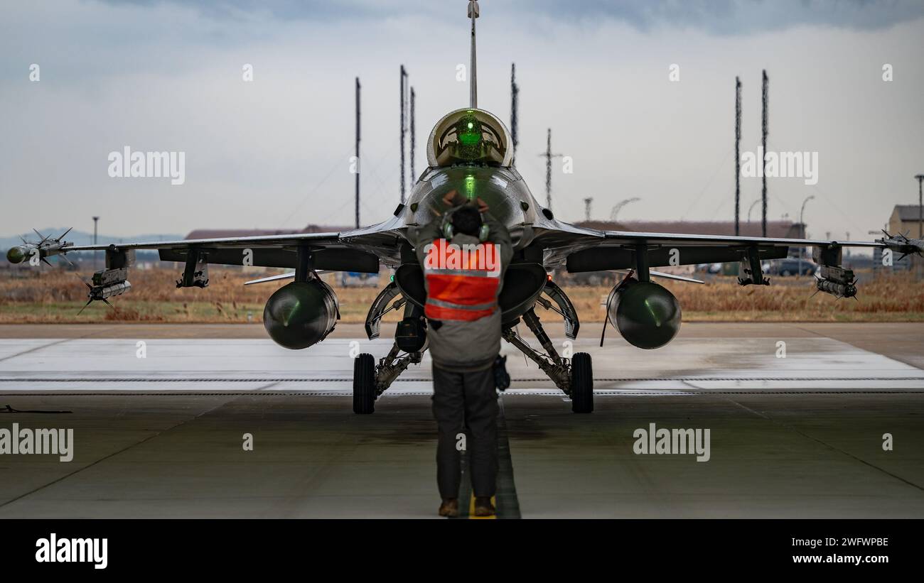 A member of the 80th Fighter Generation Squadron marshals an F-16 ...