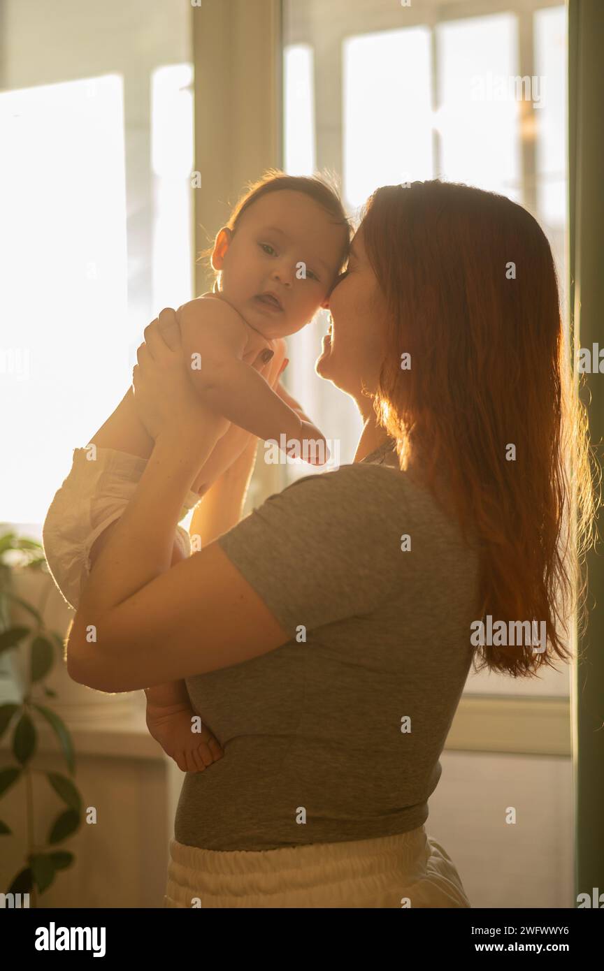 A Caucasian woman gently lifts her newborn son up. Vertical photo Stock ...