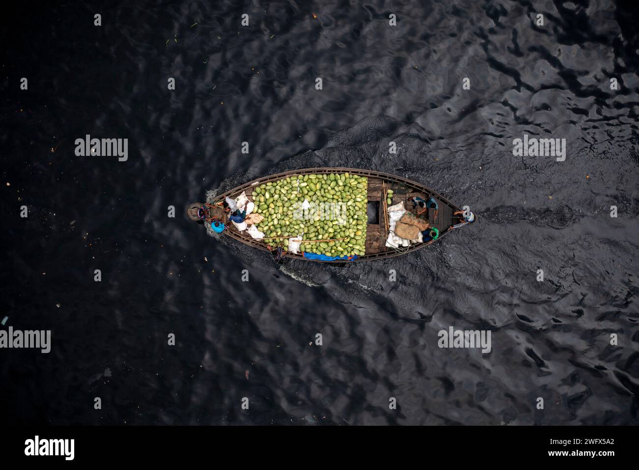 Aerial view of several small commercial boats with people unloading watermelons at Old Dhaka ...