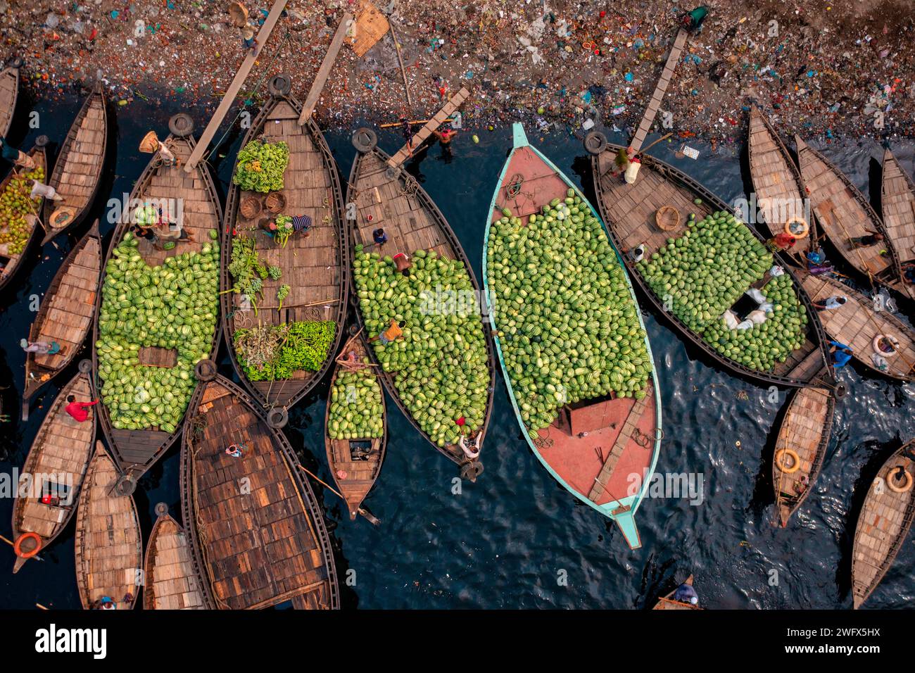 Aerial view of several small commercial boats with people unloading watermelons at Old Dhaka ...