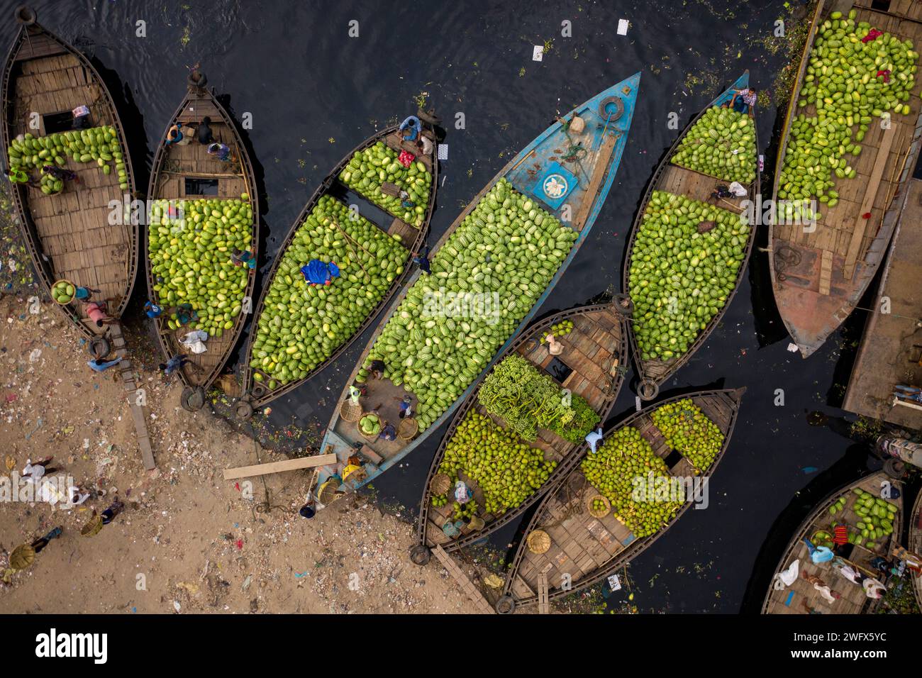 Aerial view of several small commercial boats with people unloading watermelons at Old Dhaka ...