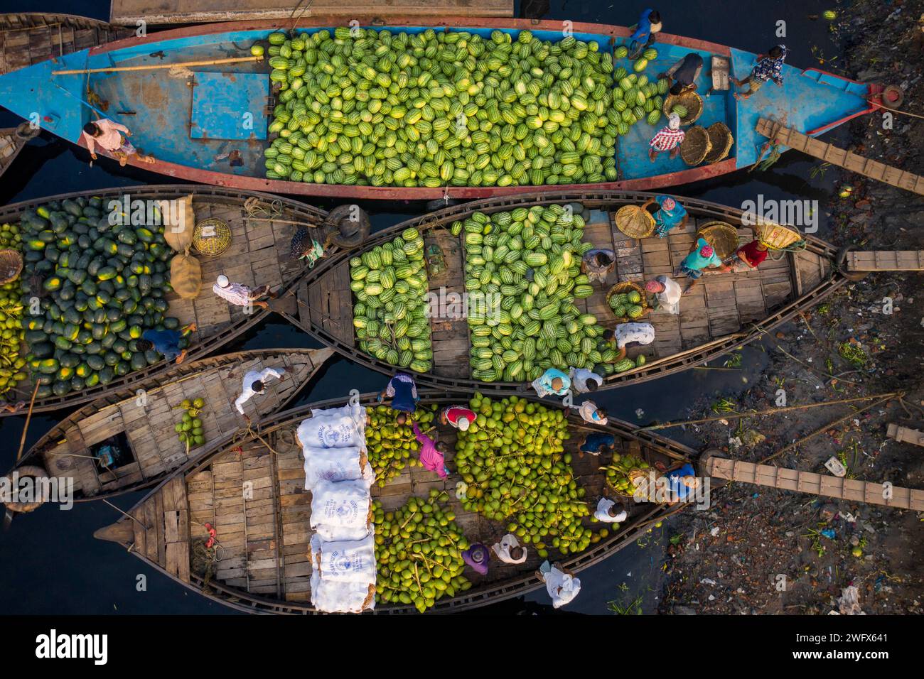 Aerial view of several small commercial boats with people unloading watermelons at Old Dhaka ...