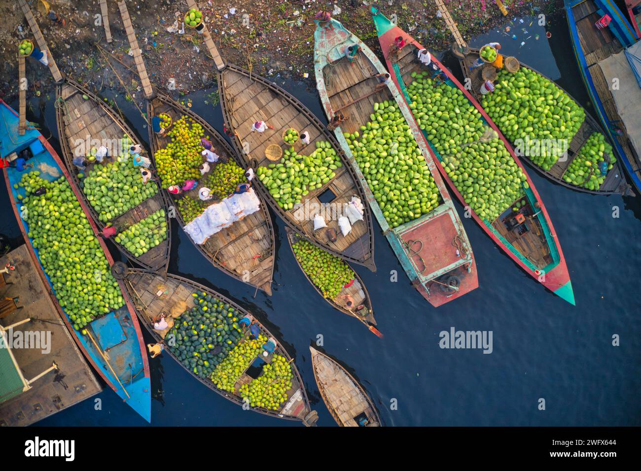 Aerial view of several small commercial boats with people unloading watermelons at Old Dhaka ...
