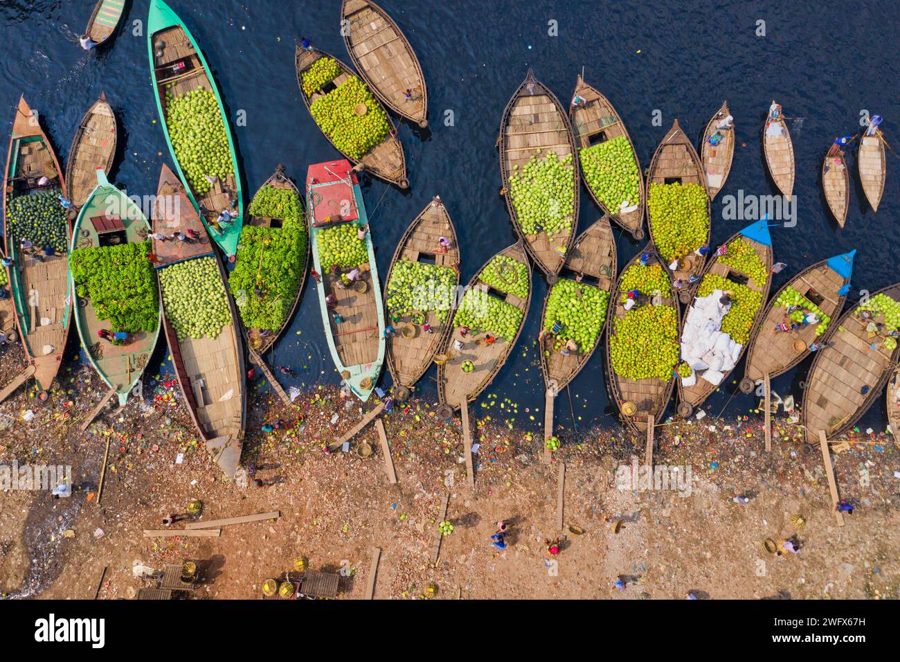 Aerial view of several small commercial boats with people unloading watermelons at Old Dhaka ...