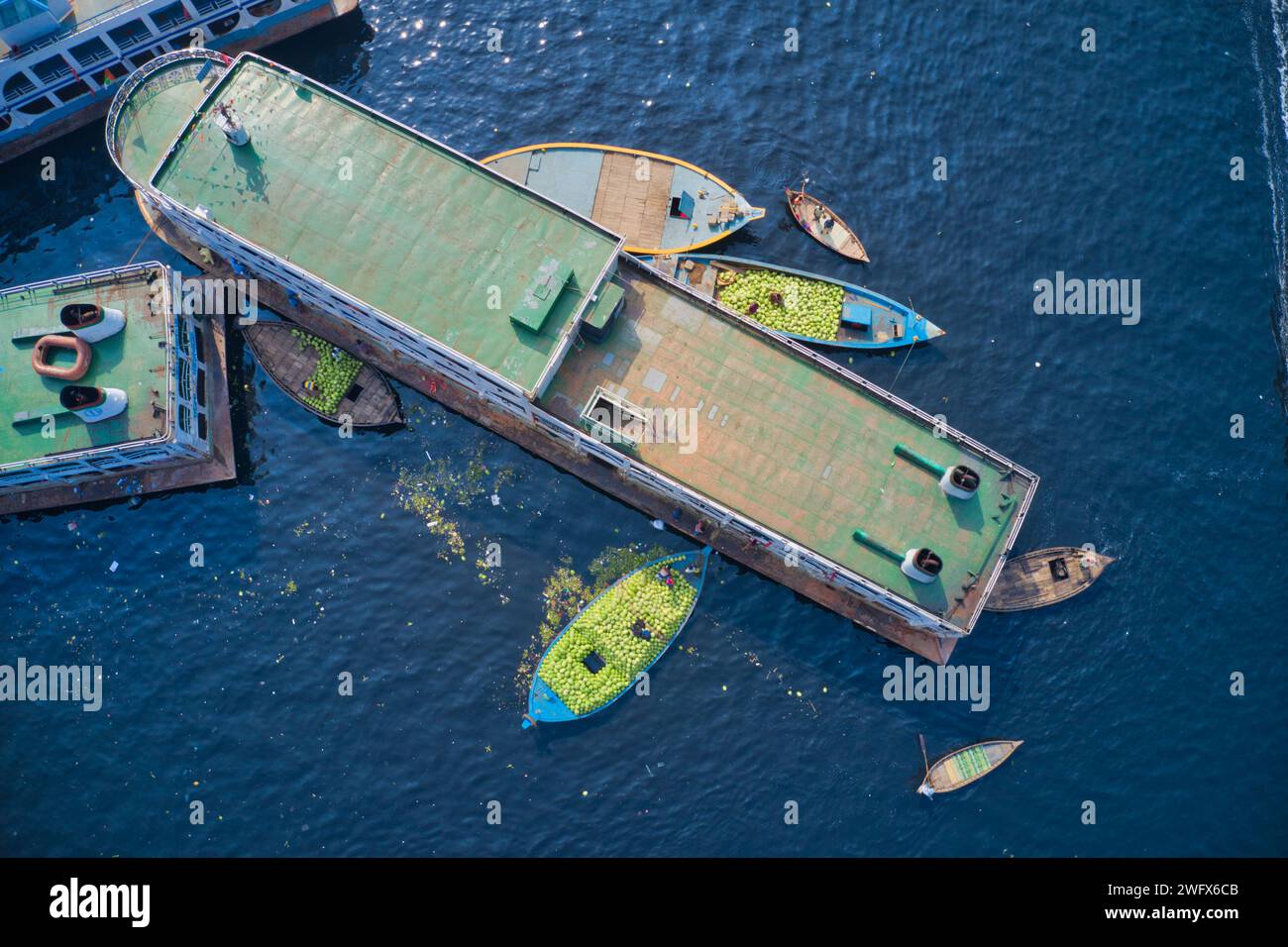 Aerial view of several small commercial boats with people unloading watermelons at Old Dhaka ...