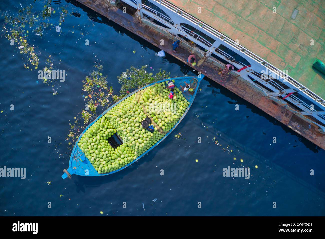 Aerial view of several small commercial boats with people unloading watermelons at Old Dhaka ...