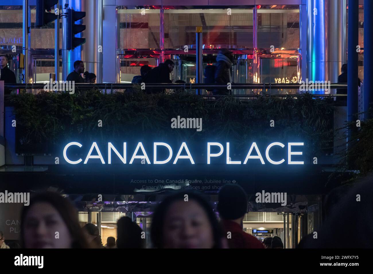 Canada Place sign lit up at night with people walking, London, England ...