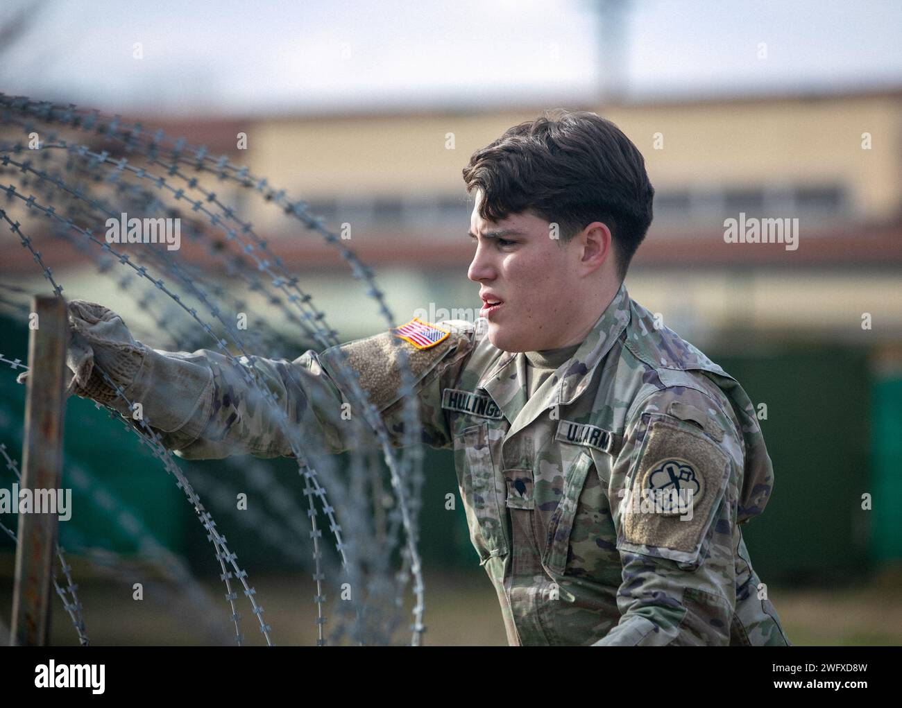 Spc. Elijah Hullinger places concertina wire around the area of ...