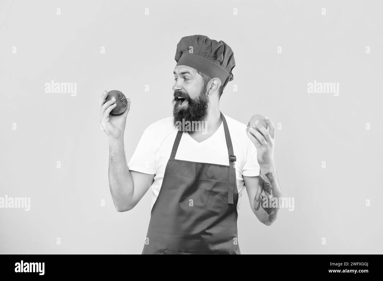Surprised guy in cooking apron and toque looking at tomatoes yellow ...