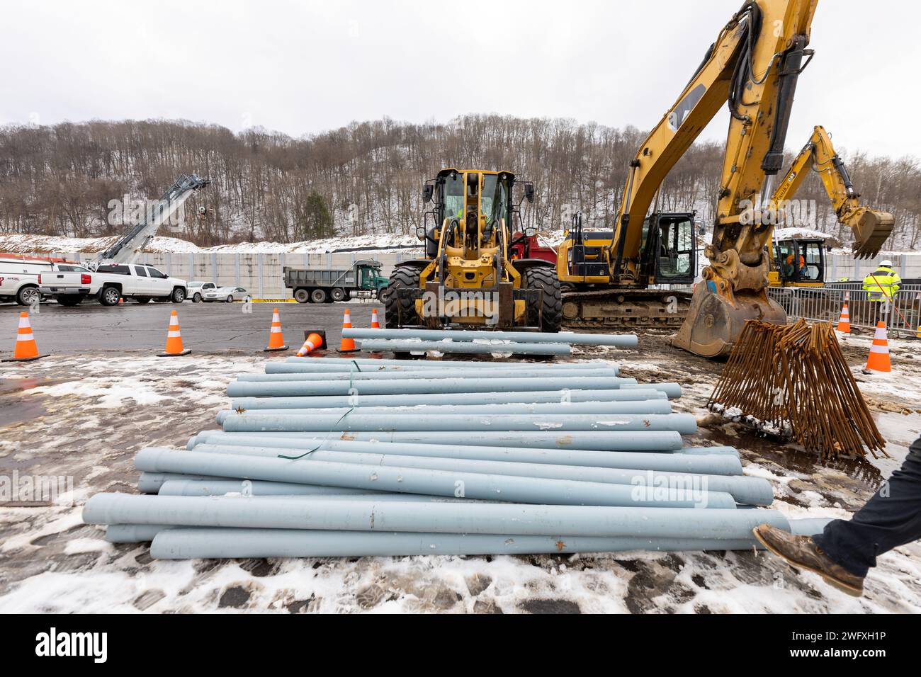 A forklift drops off a stack of pipes as a construction crew working ...