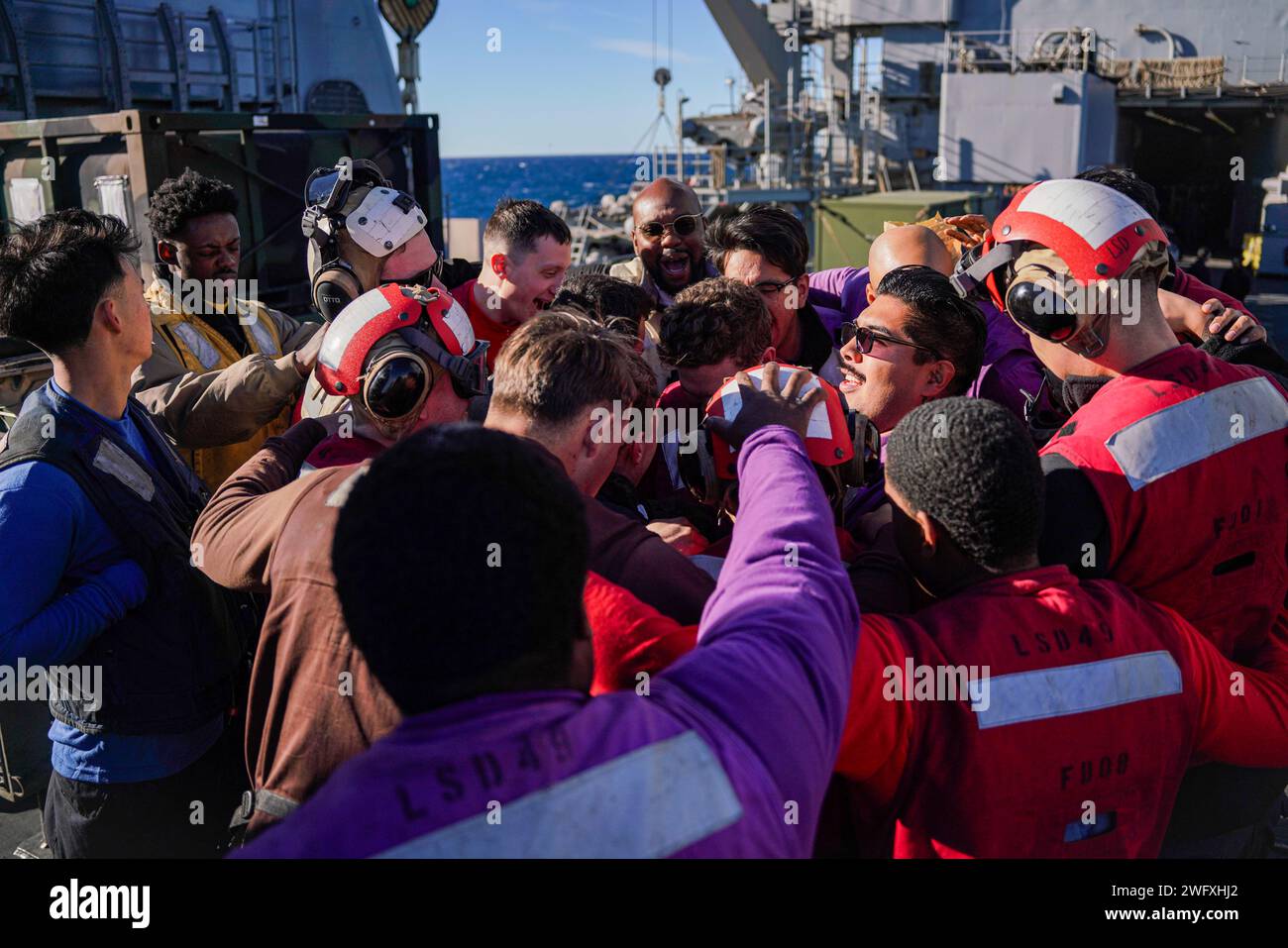 Sailors huddle together before flight quarters aboard the amphibious ...