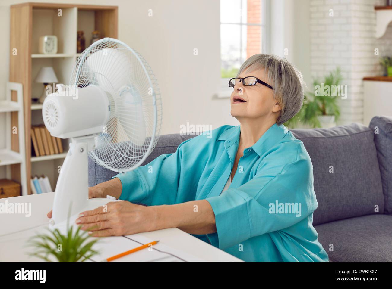 Senior woman, tired of extreme summer heat, enjoying fresh air by ...