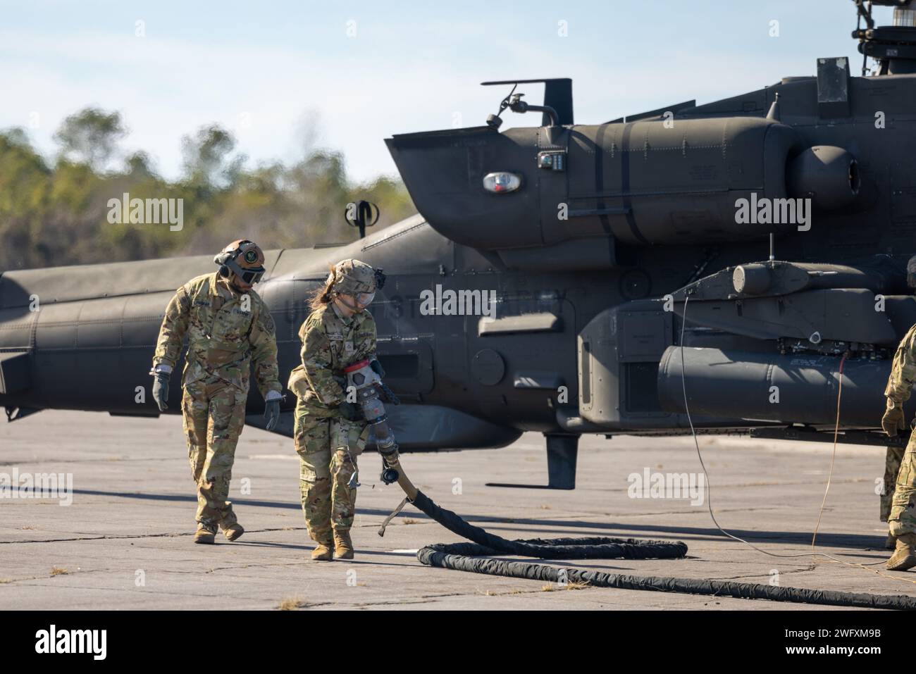 U.S. Army Soldiers pull away a fuel hose after refueling an AH-64E ...
