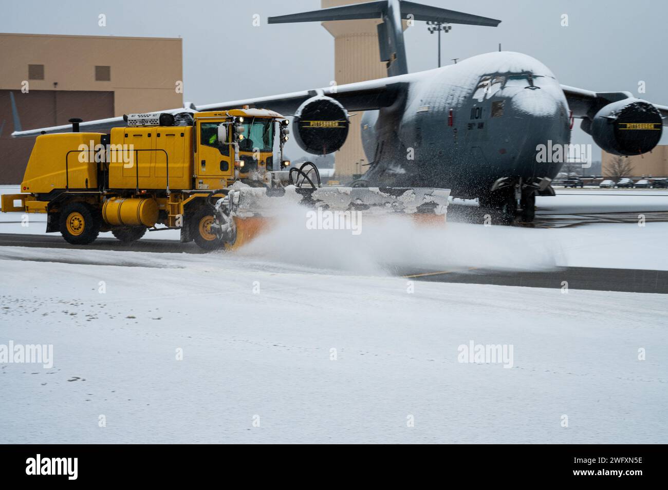 A contractor uses a "snow broom" to remove snow and ice from the flight ...