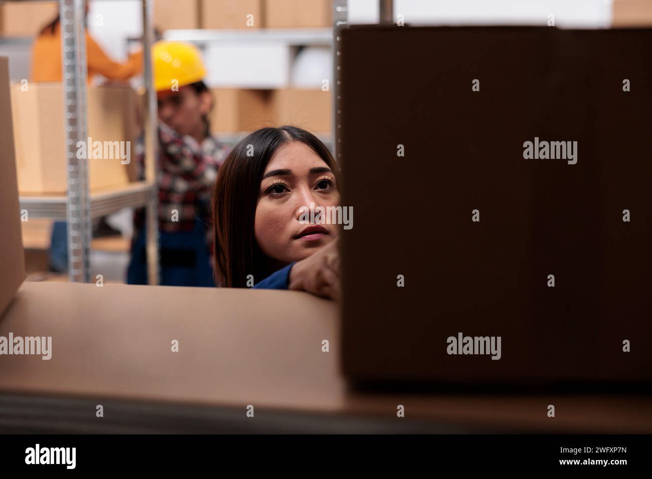 Asian woman warehouse worker doing inventory management while checking ...