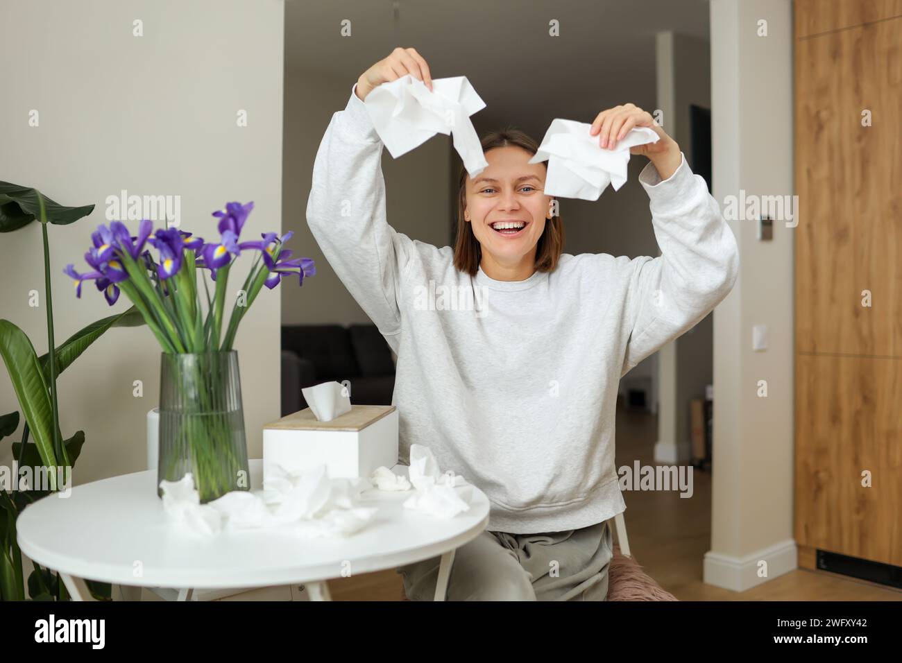 Seasonal allergy free. Happy young woman throws tissues up at home ...