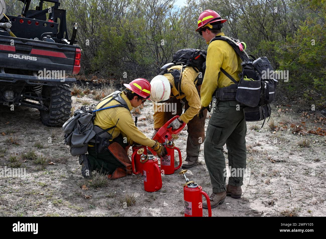 Three firefighters, with the U.S. Air Force Wildland Fire Branch, fill ...