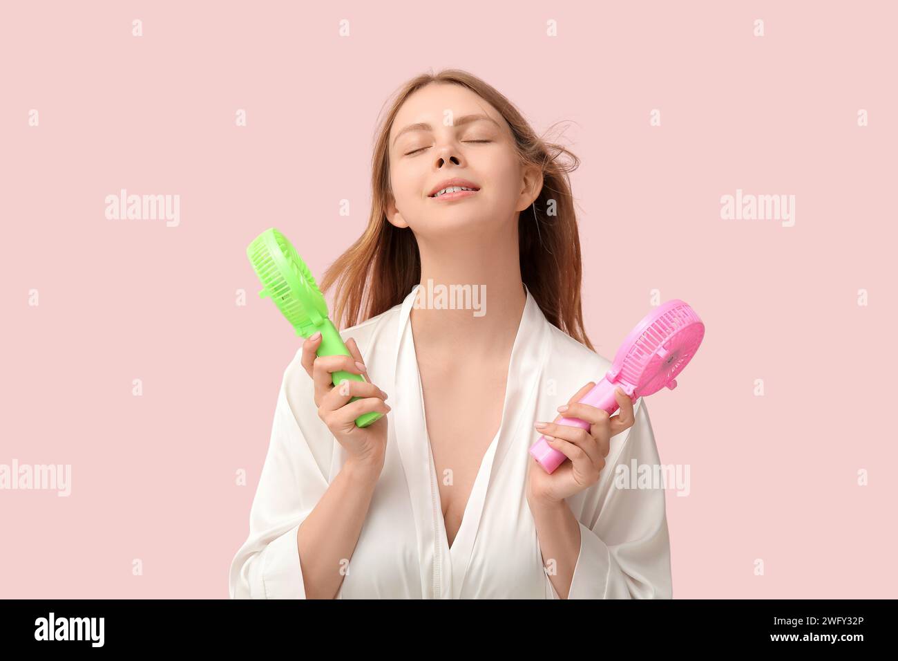 Beautiful young woman with handheld mini fans on pink background Stock ...