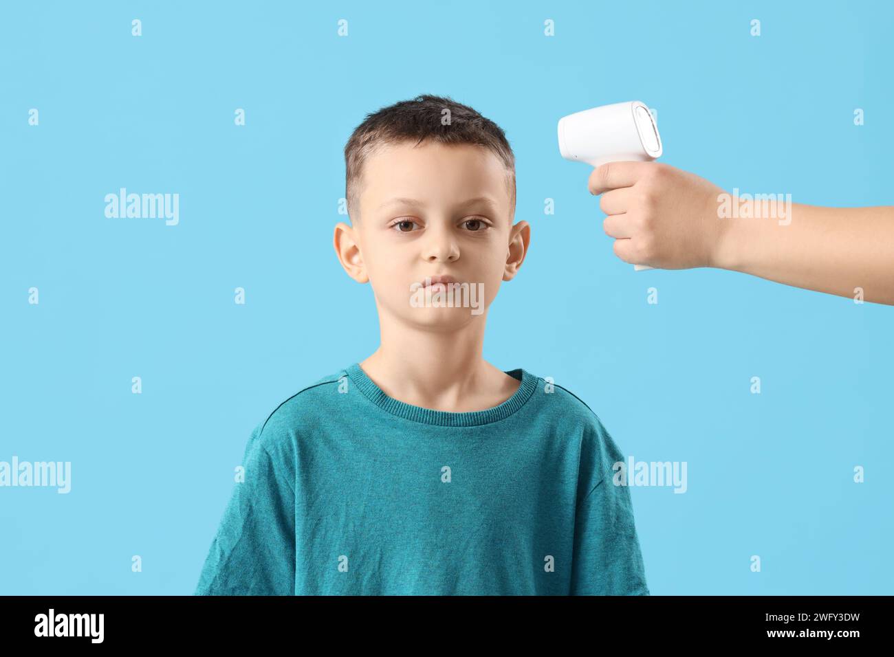 Ill little boy and woman with infrared thermometer measuring his ...