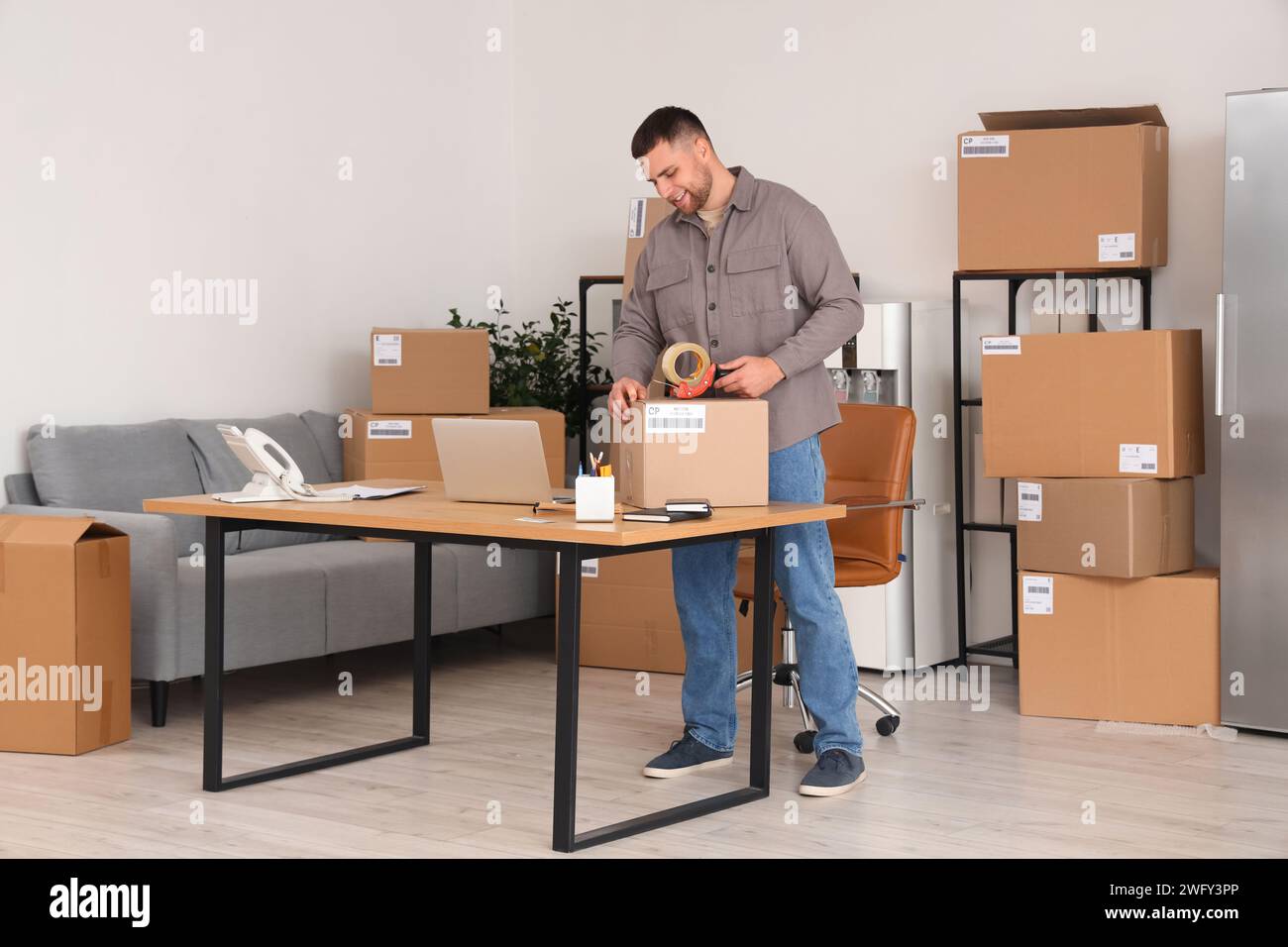 Male seller packing parcel box with tape in warehouse store Stock Photo ...