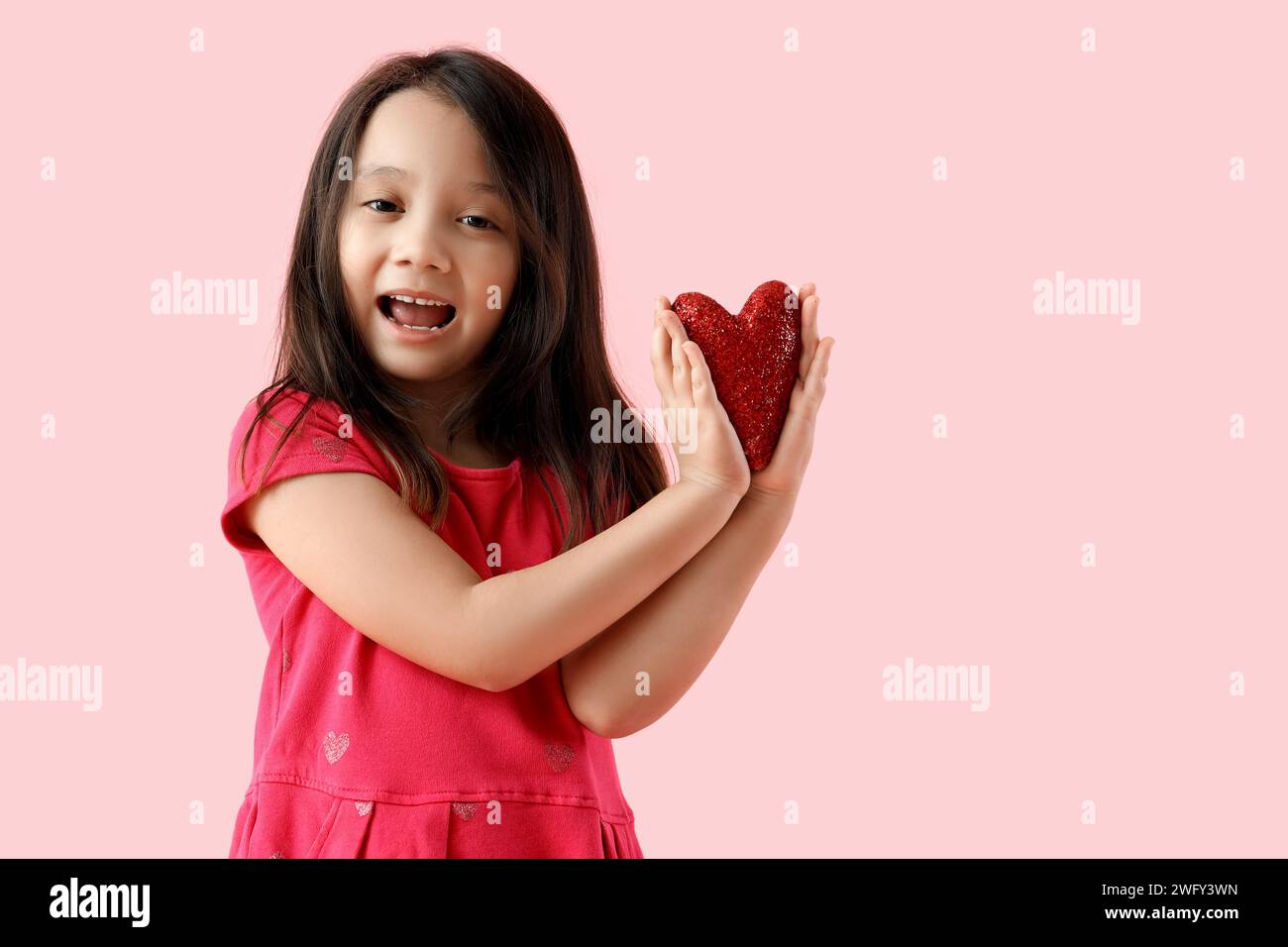Cute little Asian girl with heart on pink background. Valentine's Day ...
