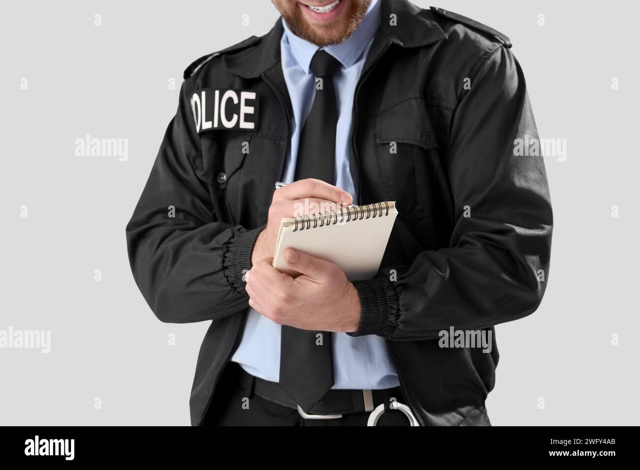 Male police officer with notebook on grey background Stock Photo - Alamy