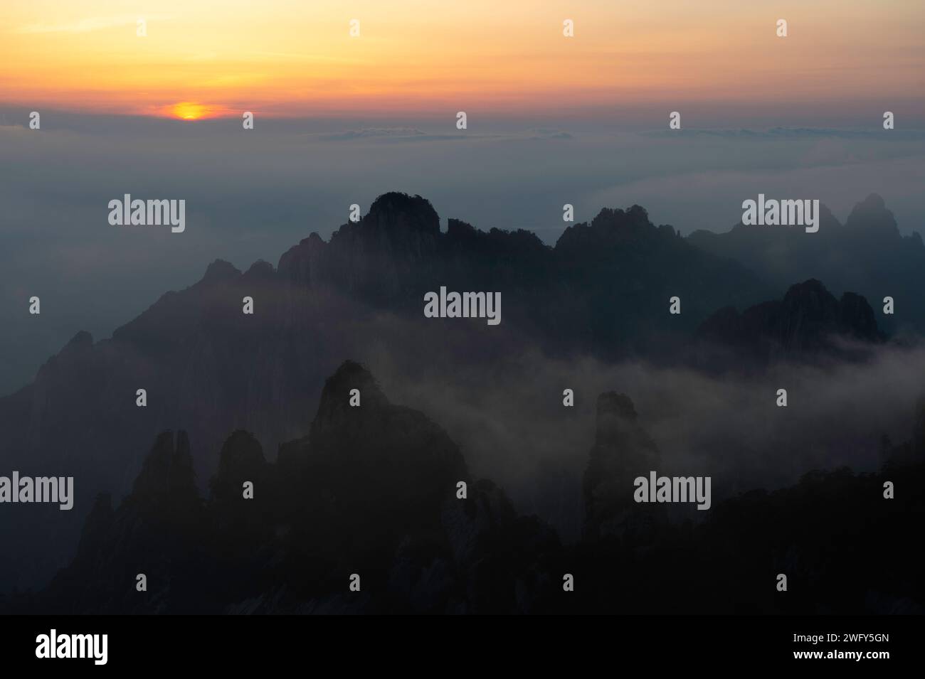 A golden sun sets above the Sea of Clouds as viewed from Turtle Peak in the Huangshan Yellow ...