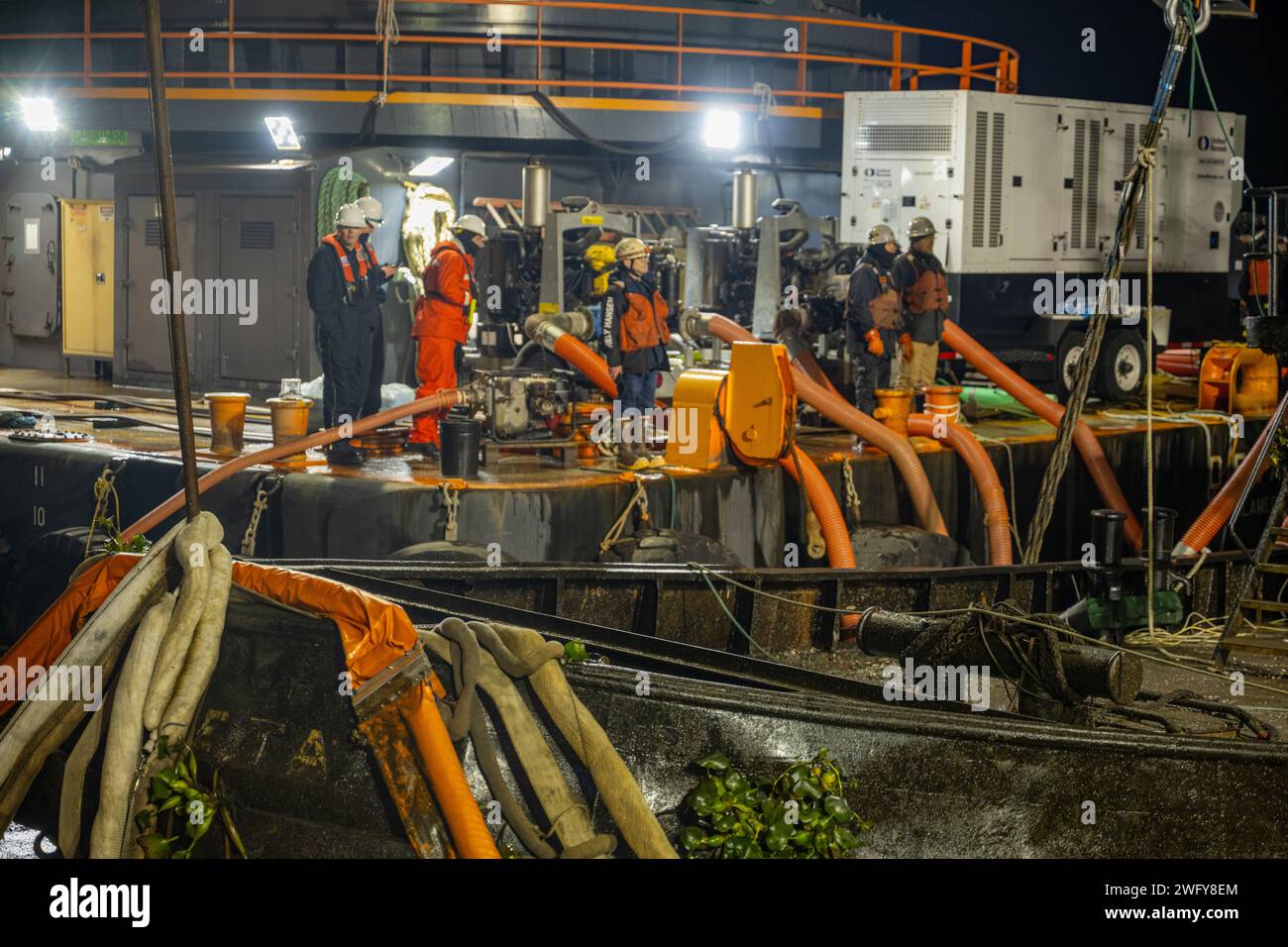 Coast Guard CERT officers and contractors watch the dewatering process ...
