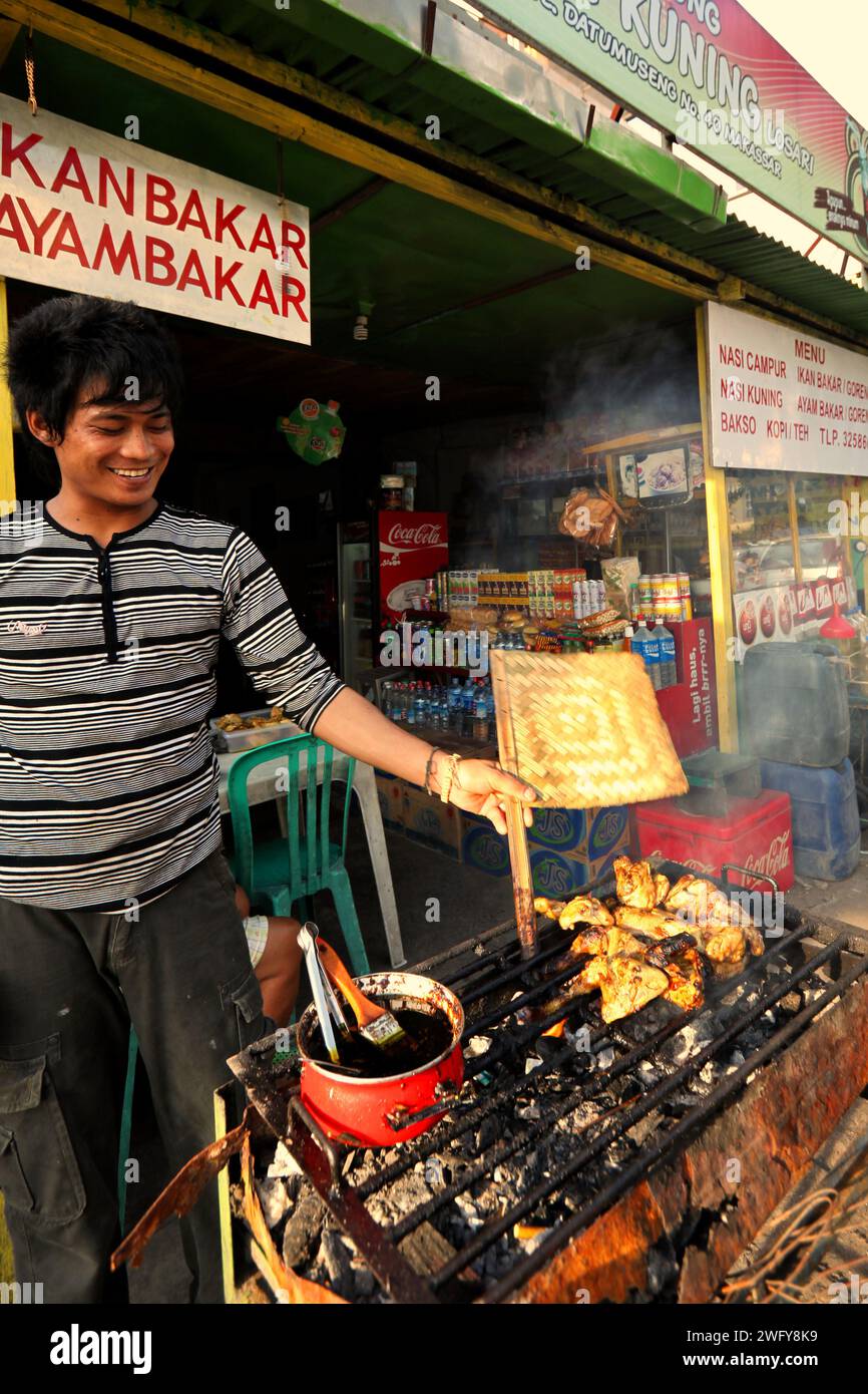 A worker grills chicken meat in front of a roadside vendor at a center ...