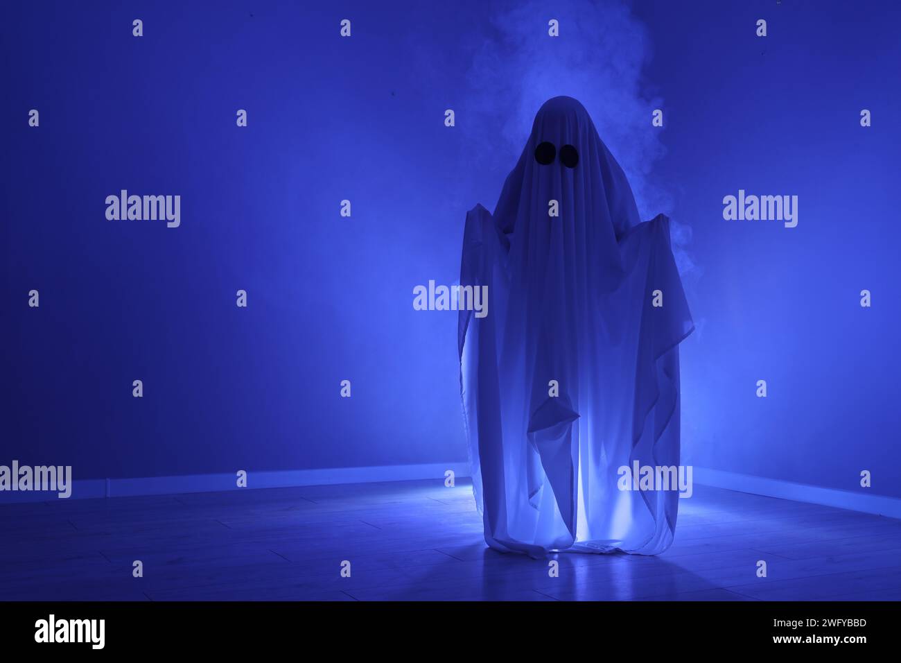 Creepy ghost. Woman covered with sheet in blue light, space for text ...