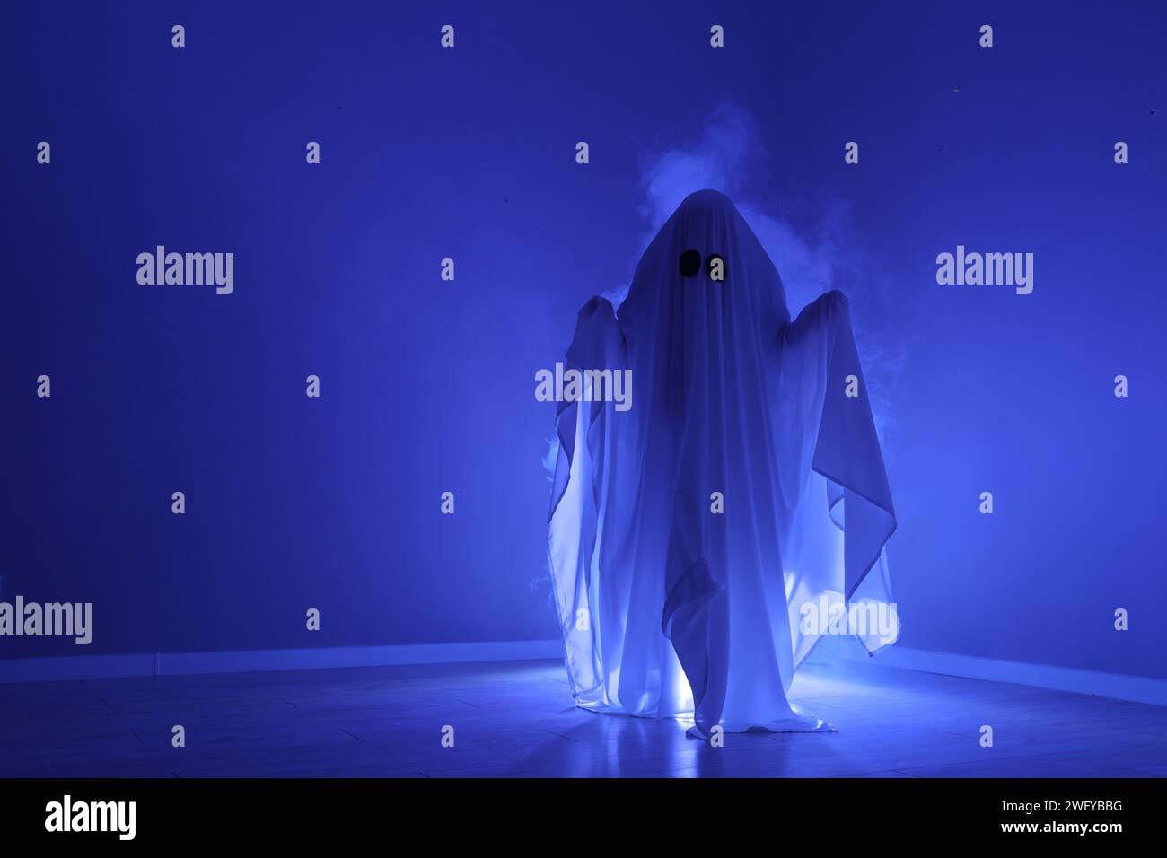 Creepy ghost. Woman covered with sheet in blue light, space for text ...