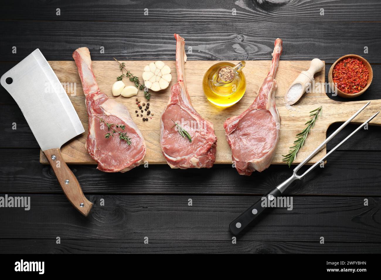 Fresh tomahawk beef cuts, spices and butcher tools on black wooden ...