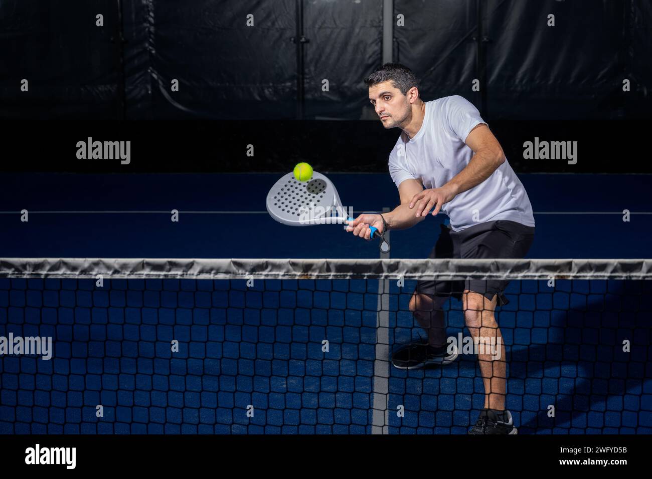 Man playing padel in a blue indoor padel court padel - Young sporty boy ...