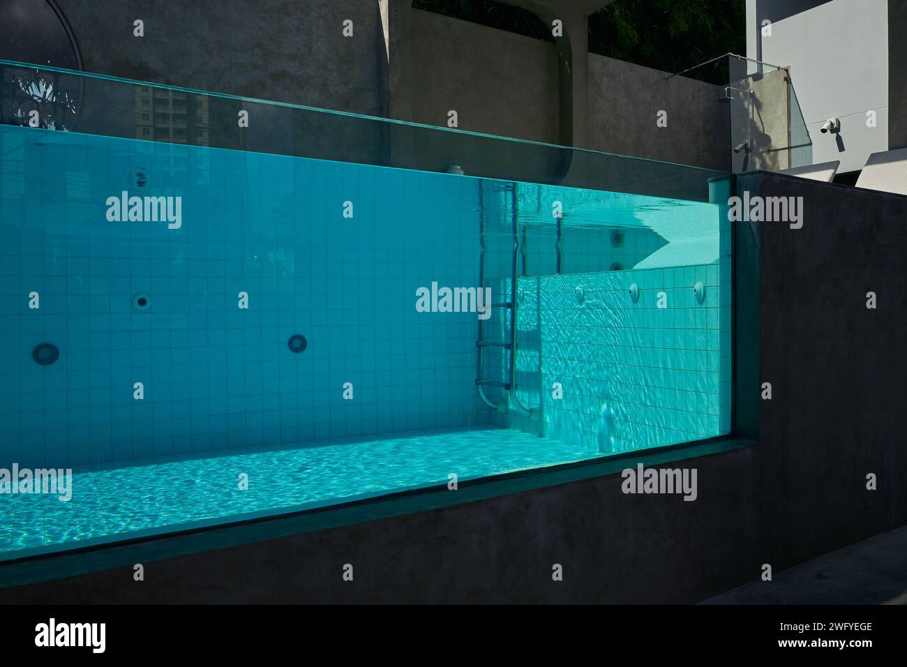 Mini swimming pool with clear blue water and trasparent glass wall edge ...